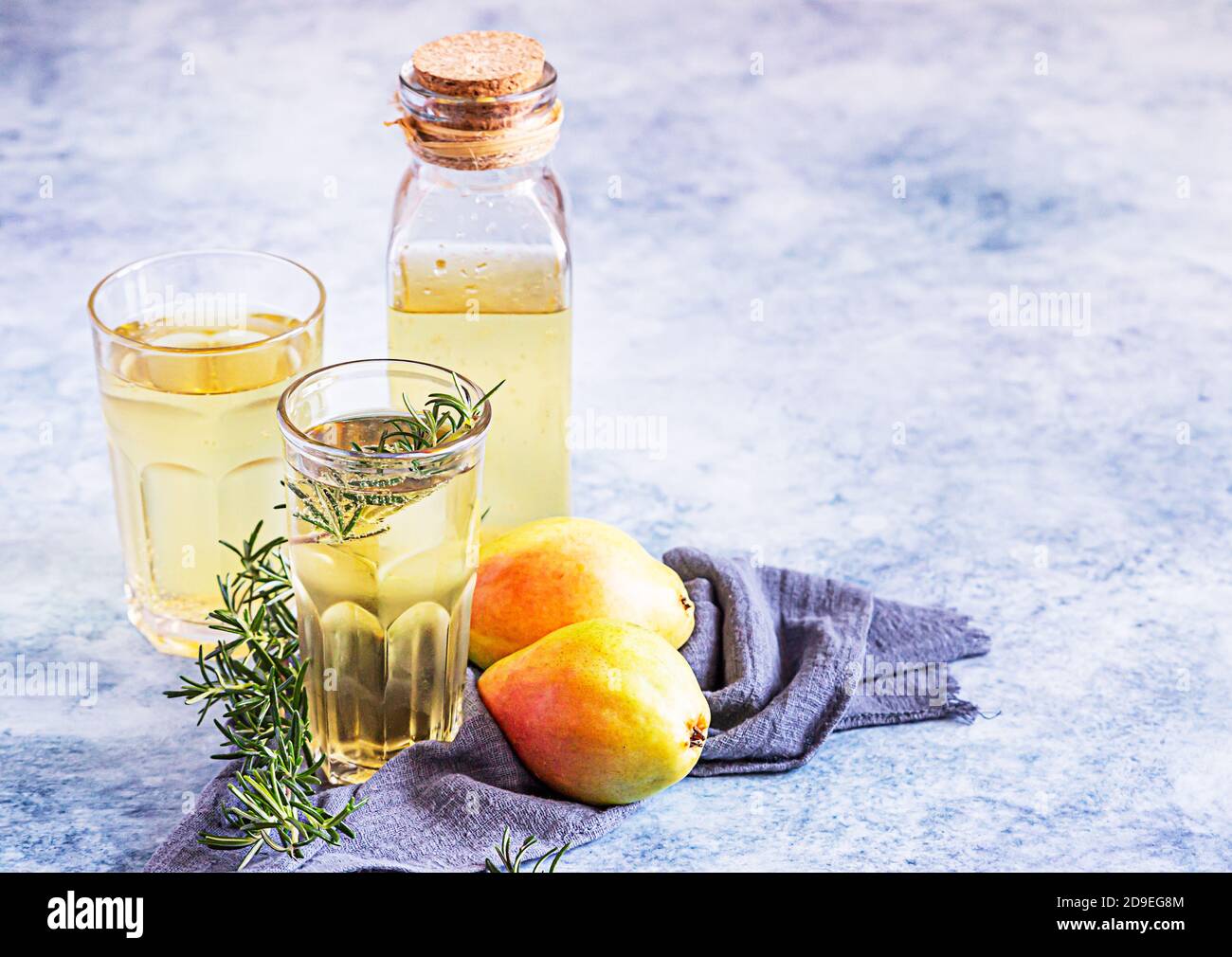 Pear cider cocktail with rosemary in tall glasses and bottle and fresh ...