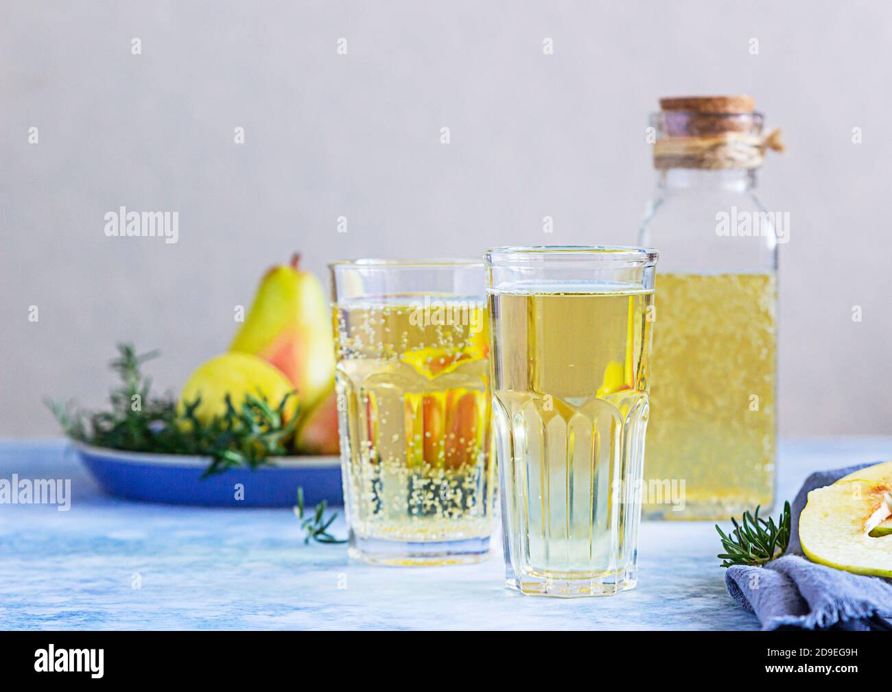 Pear cider cocktail with rosemary in tall glasses and bottle and fresh ...