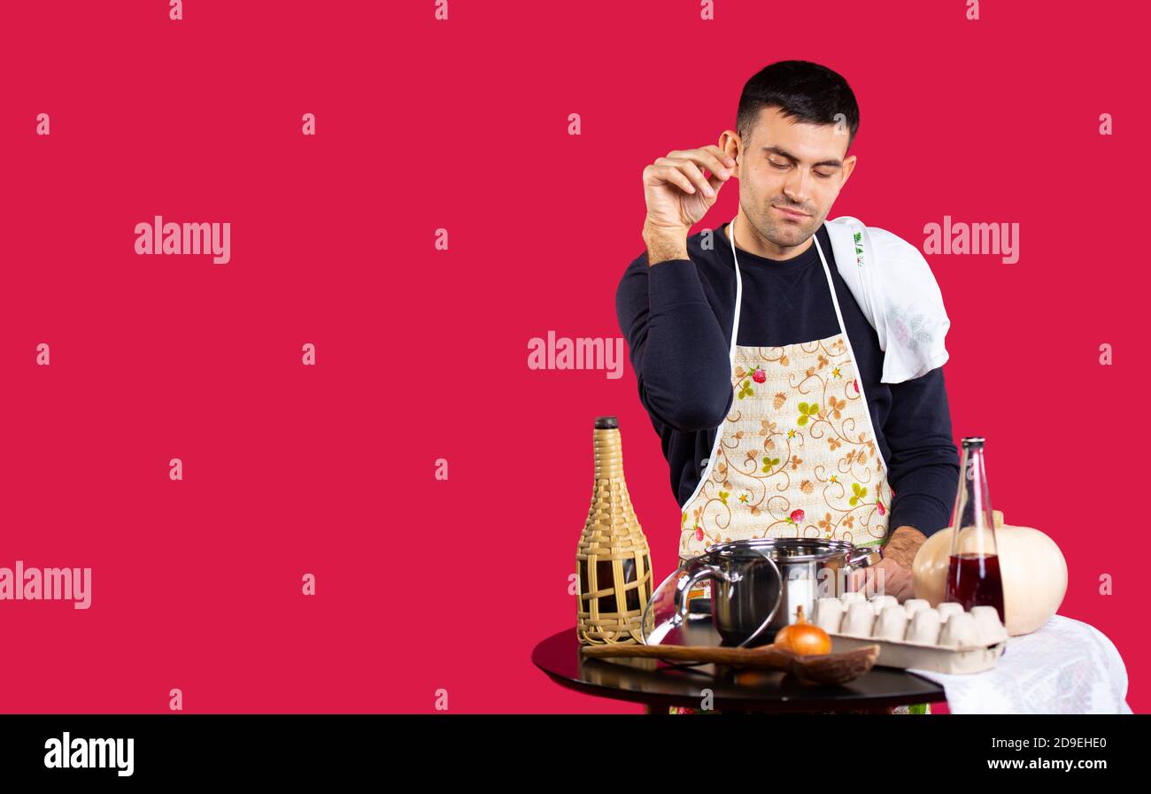 Young man pour salt and seasoning into a saucepan. Photo on a pink ...