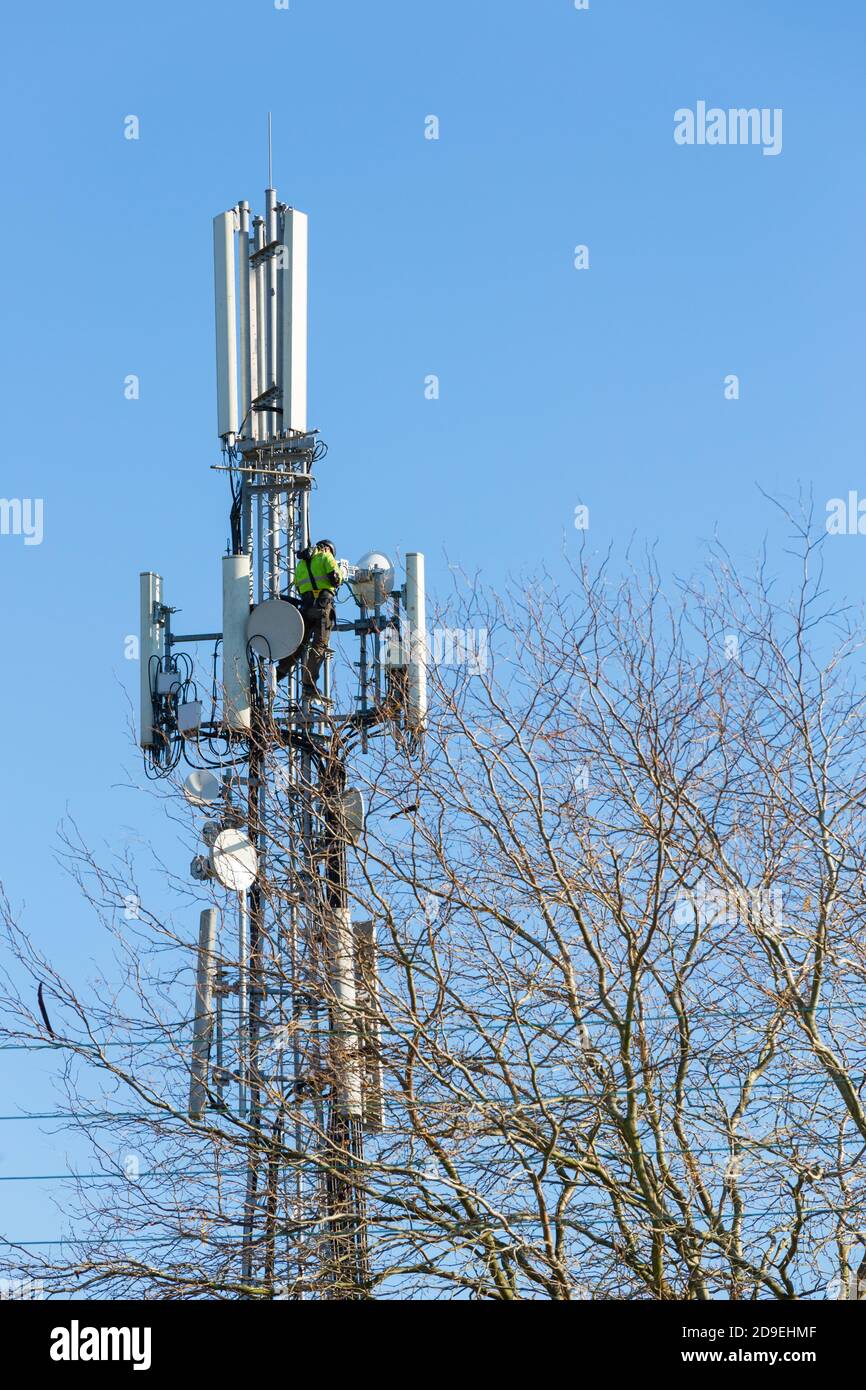 Telecoms engineer working at height on telecommunications mast ...