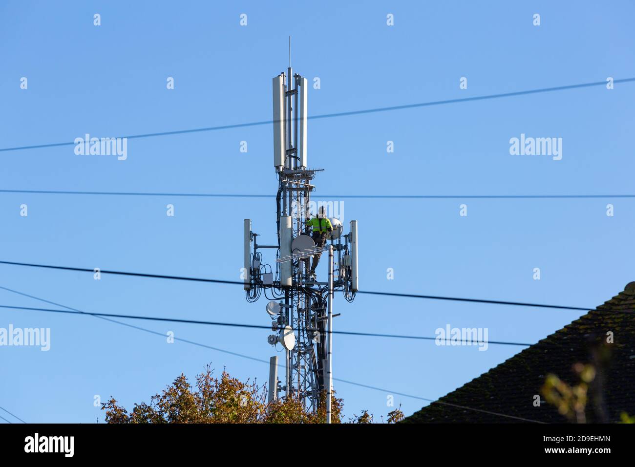 Telecoms engineer working at height on telecommunications mast ...