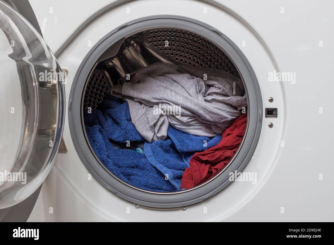 Open door in washing machine with laundry inside Stock Photo - Alamy