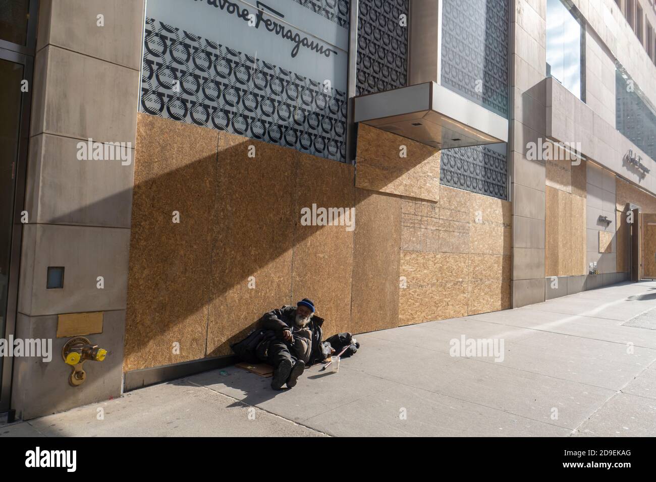 Homeless lays down on the sidewalk beside the boarded up stores New ...