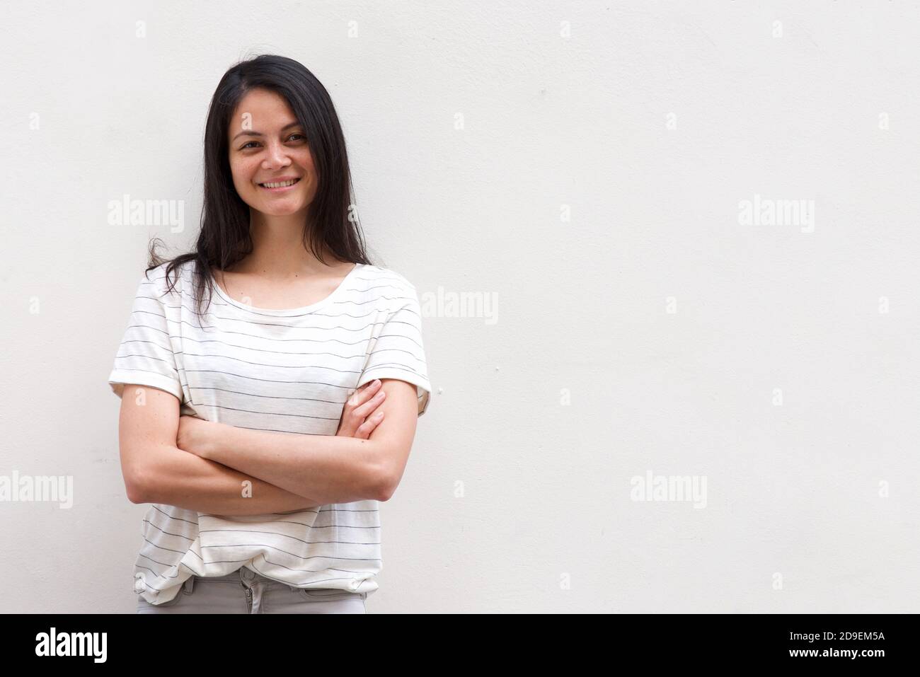 Portrait Smiling Young Asian Woman With Arms Crossed Against White Portrait Smiling Young Asian Woman With Arms Crossed Against White