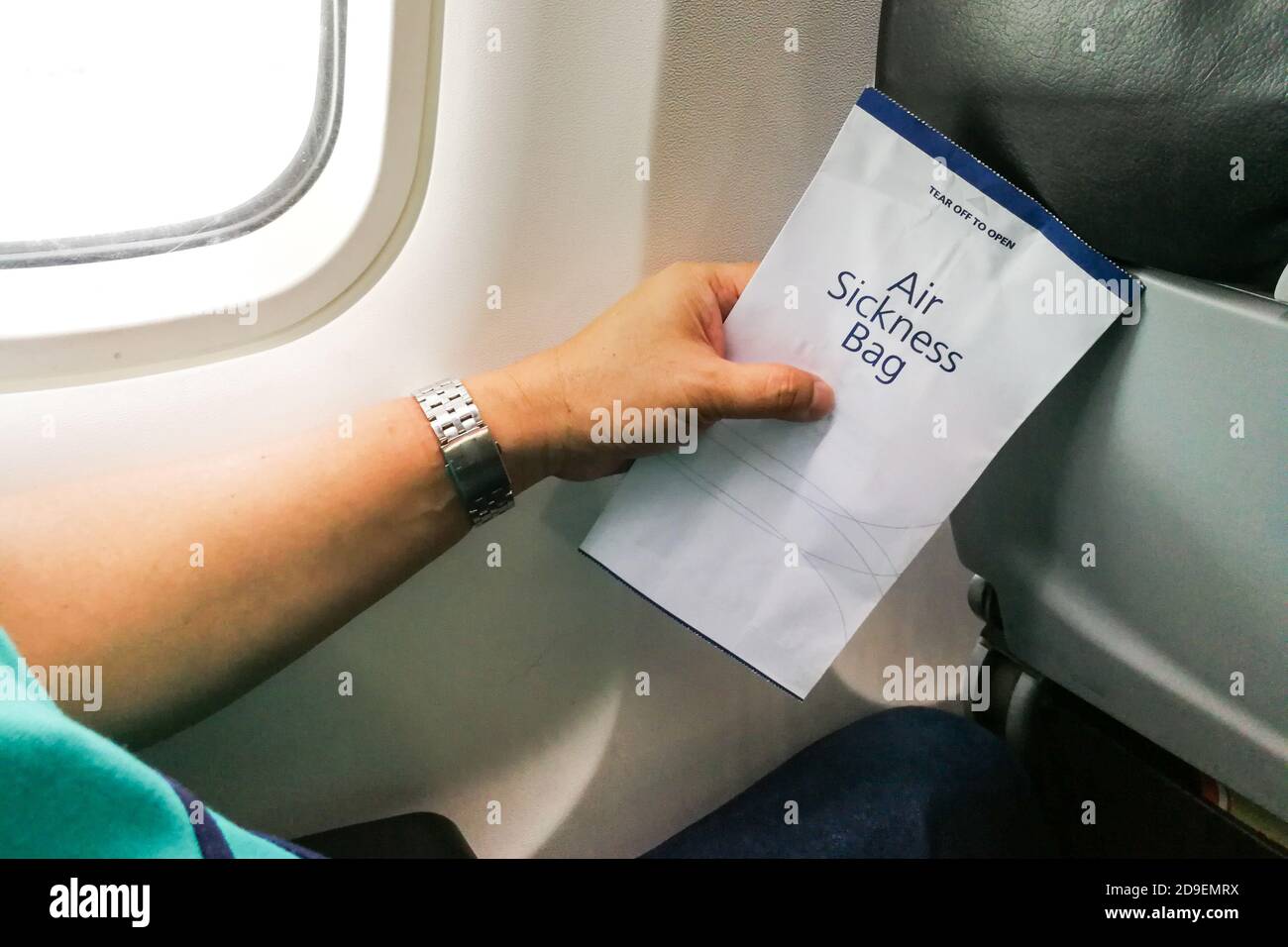 Passenger holding air sickness vomit bag in airplane Stock Photo - Alamy