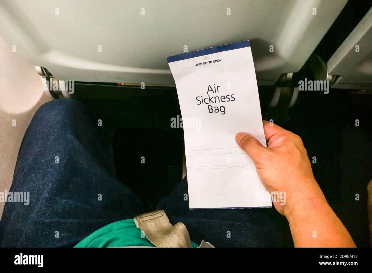 Passenger holding air sickness vomit bag in airplane Stock Photo - Alamy