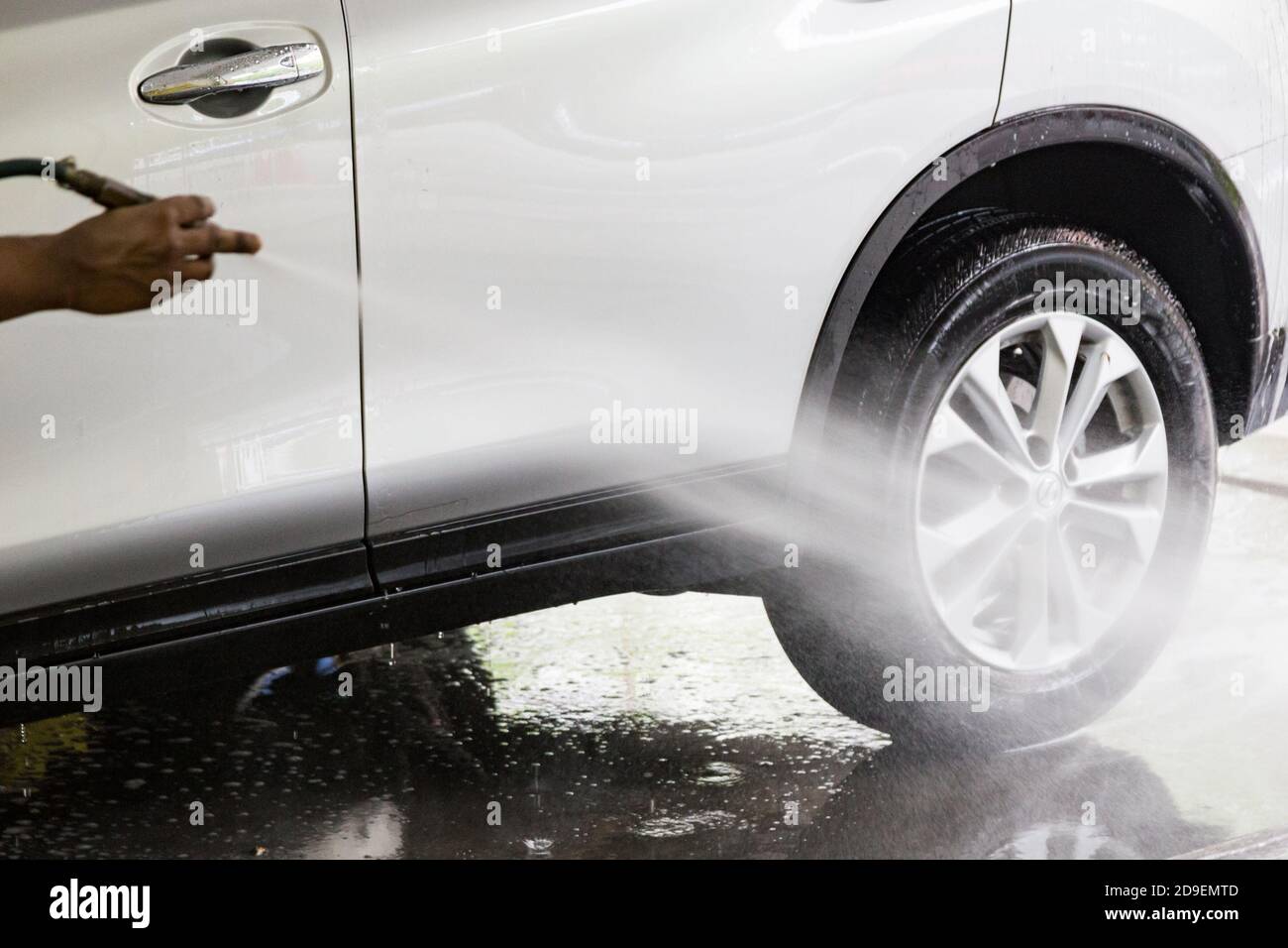 Worker spraying water onto car to wash Stock Photo - Alamy