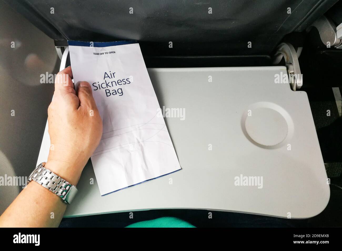 Passenger holding air sickness vomit bag in airplane Stock Photo - Alamy