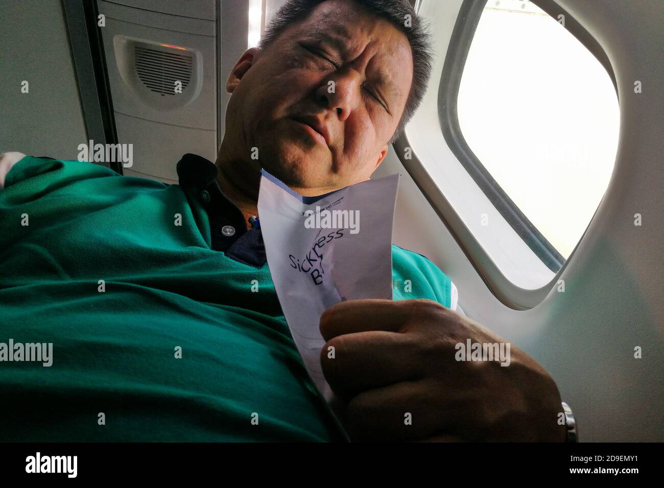 Suffering Asian man holding air sickness vomit bag in airplane Stock ...