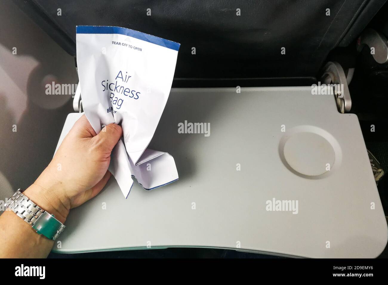 Passenger holding air sickness vomit bag in airplane Stock Photo - Alamy