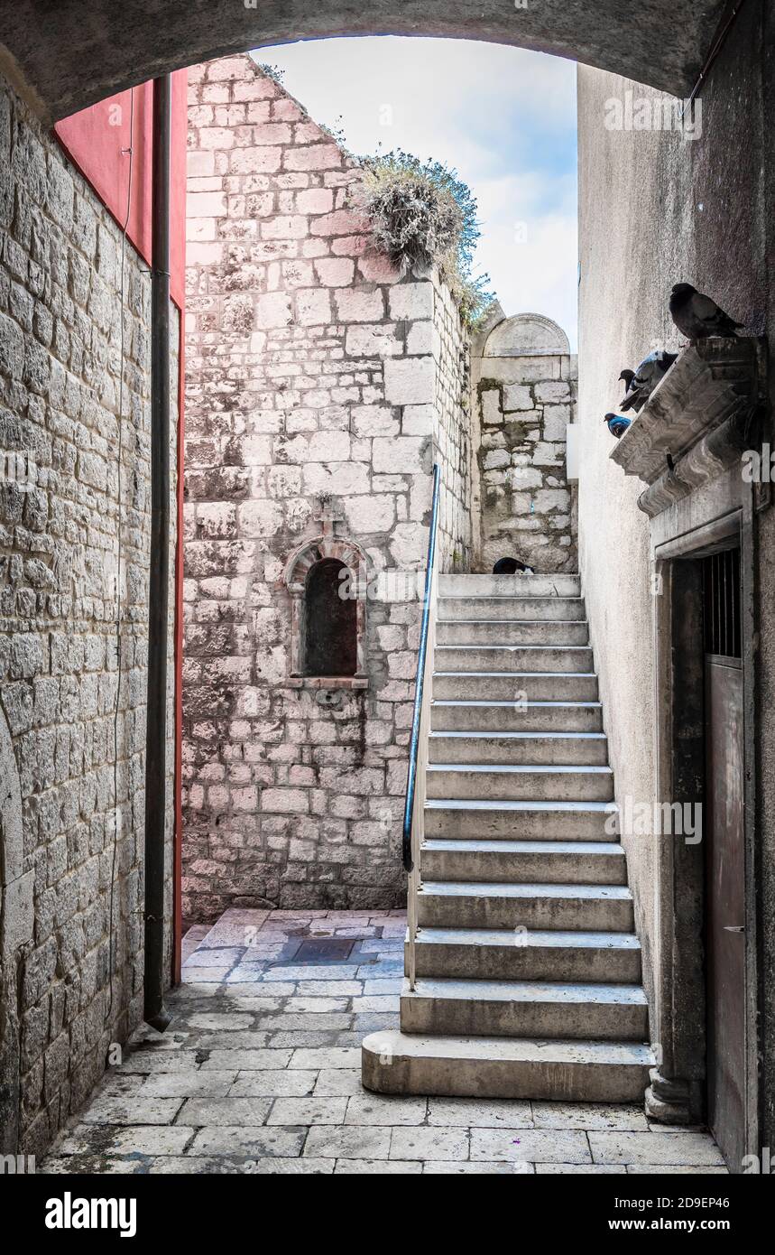 Medieval narrow street with a turn and a niche with a cross in Sibenik ...