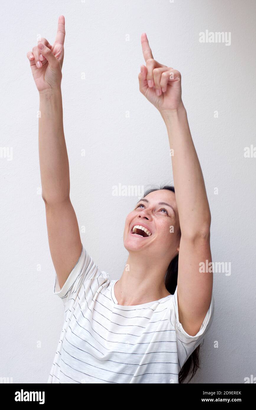 Portrait cheerful young asian woman with raised arms and fingers ...