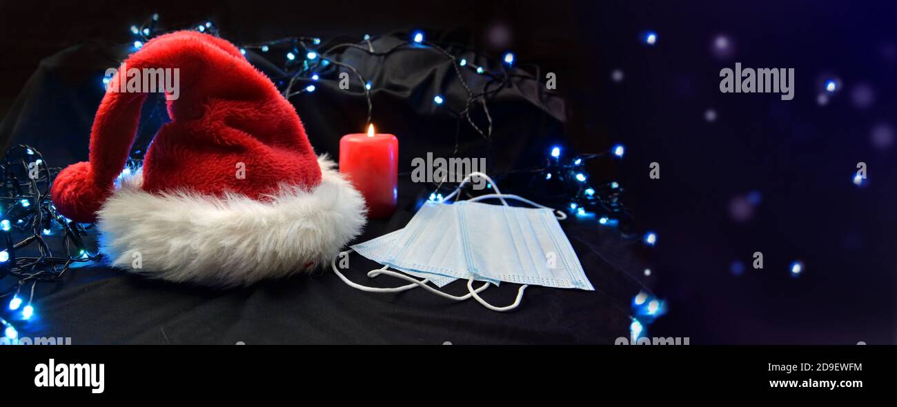 face masks put on next to a red santa claus hat and a candle in blur ...