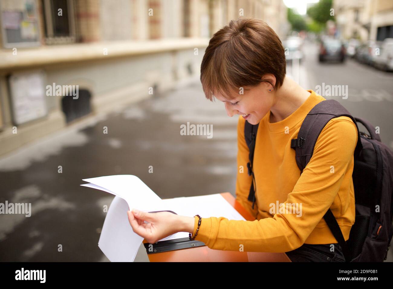 Side portrait female college student sitting outside looking at notes ...