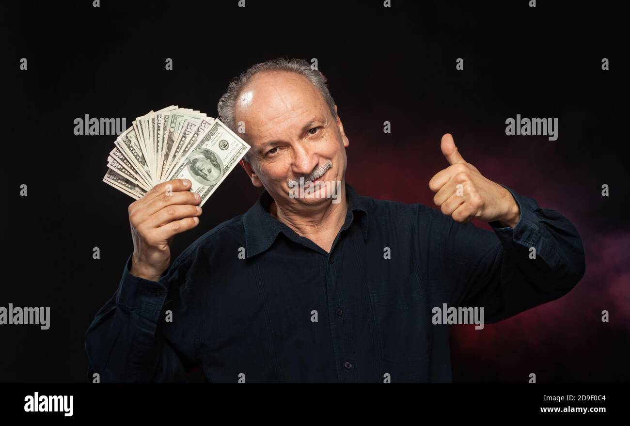 Senior gentleman holding a stack of money. Portrait of an excited old ...