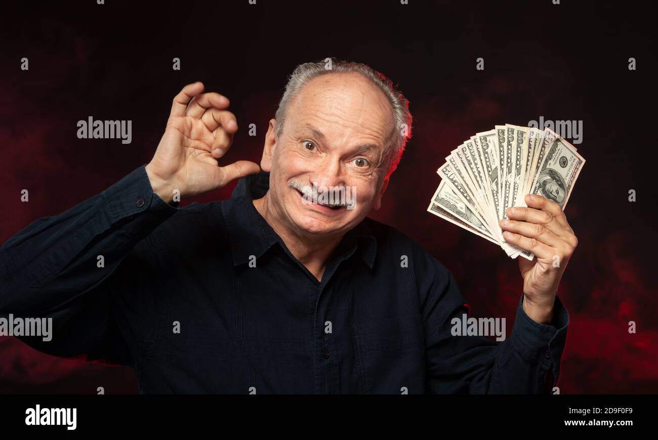 Senior gentleman holding a stack of money. Portrait of an excited old ...