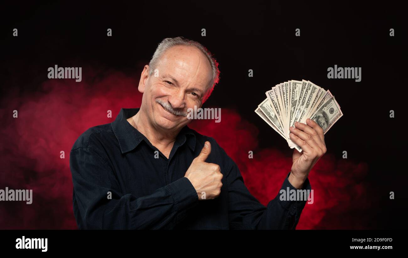 Senior gentleman holding a stack of money. Portrait of an excited old ...