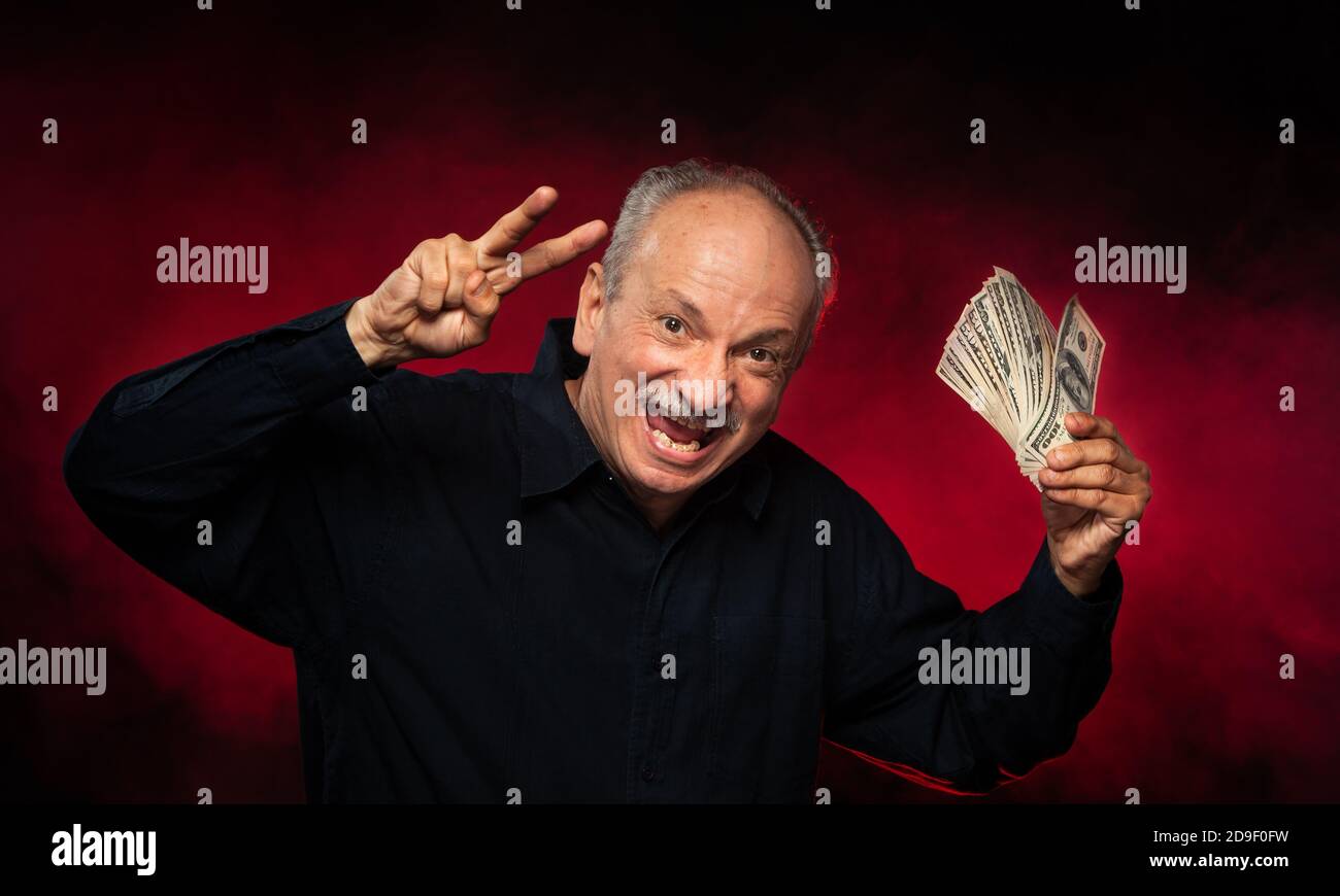 Senior gentleman holding a stack of money. Portrait of an excited old ...