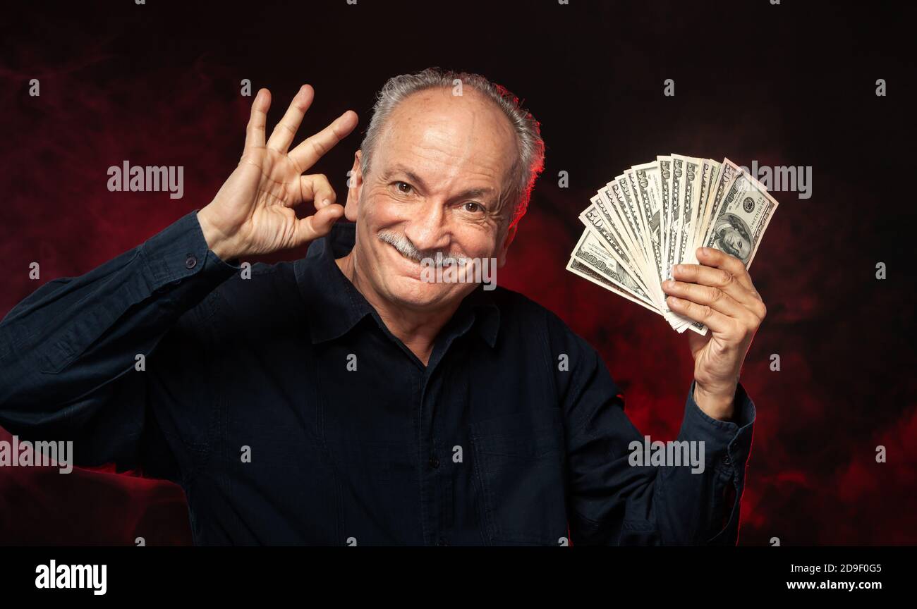 Senior gentleman holding a stack of money. Portrait of an excited old ...