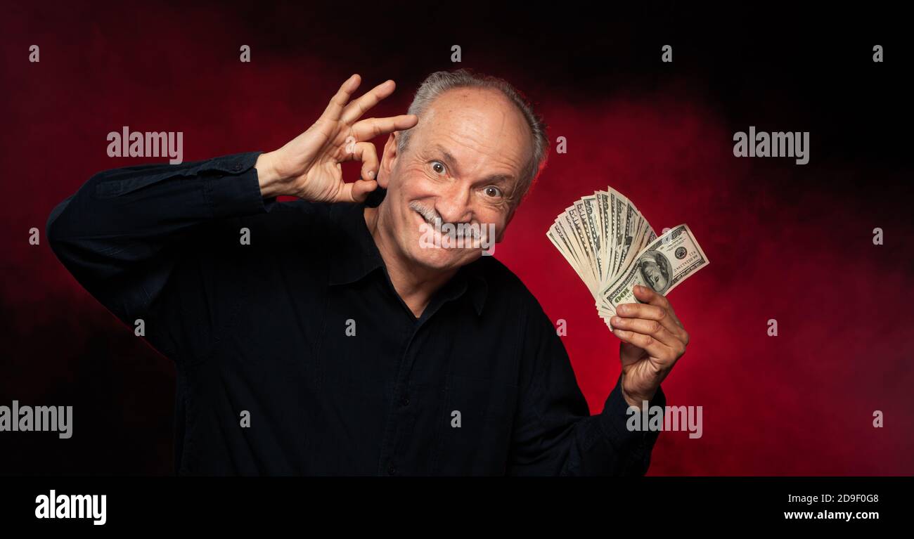 Senior gentleman holding a stack of money. Portrait of an excited old ...