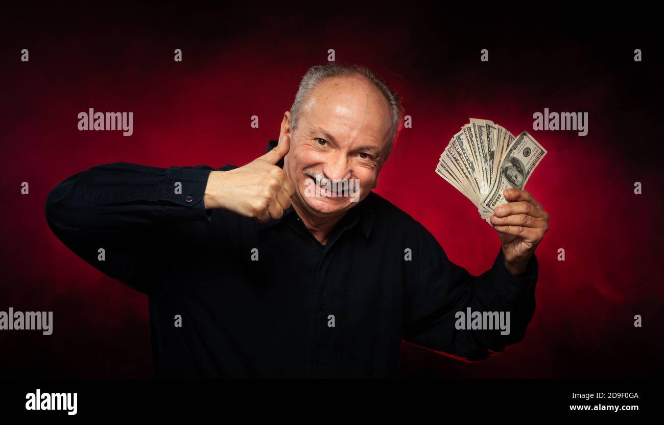 Senior gentleman holding a stack of money. Portrait of an excited old ...