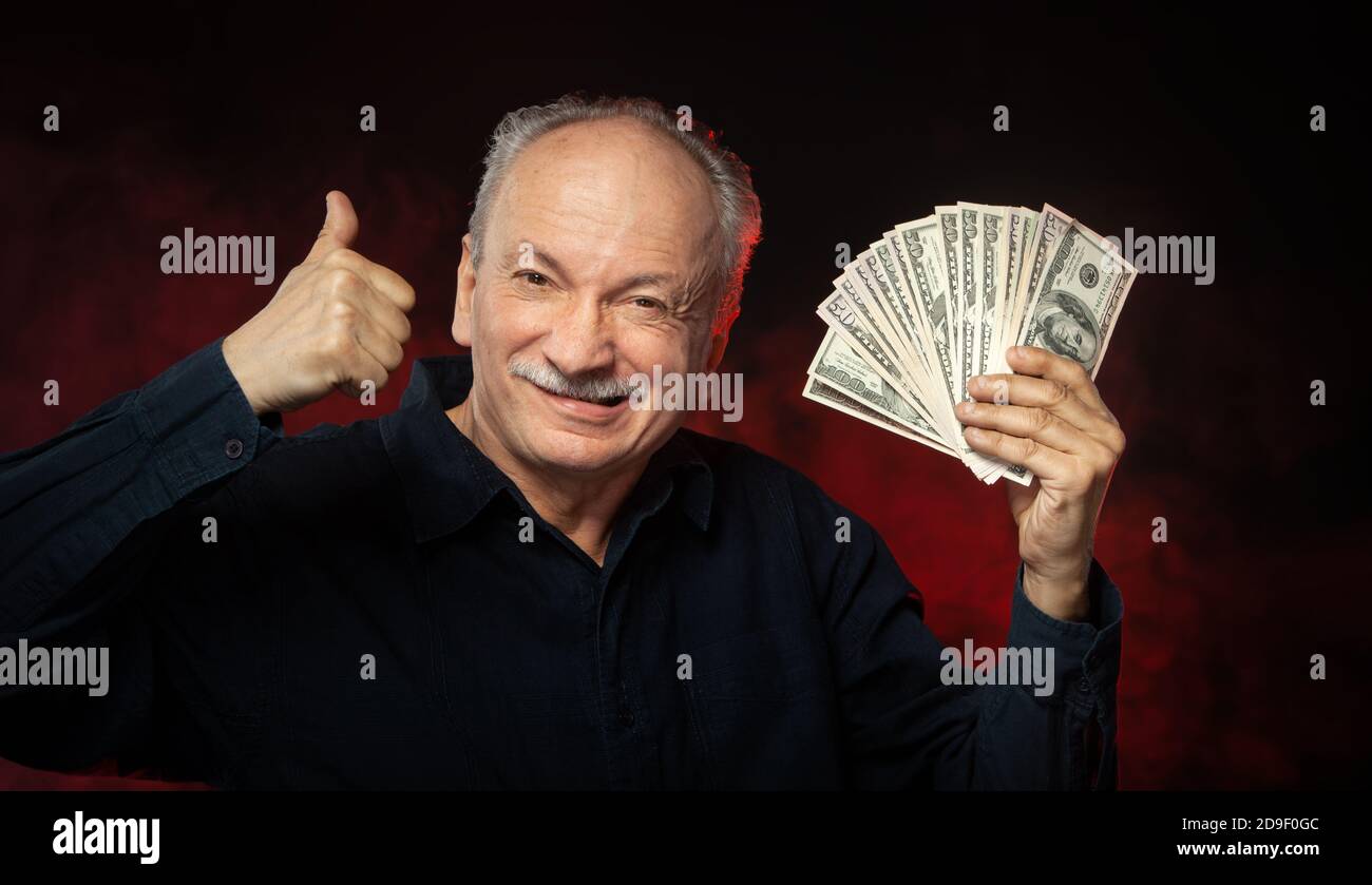 Senior gentleman holding a stack of money. Portrait of an excited old ...