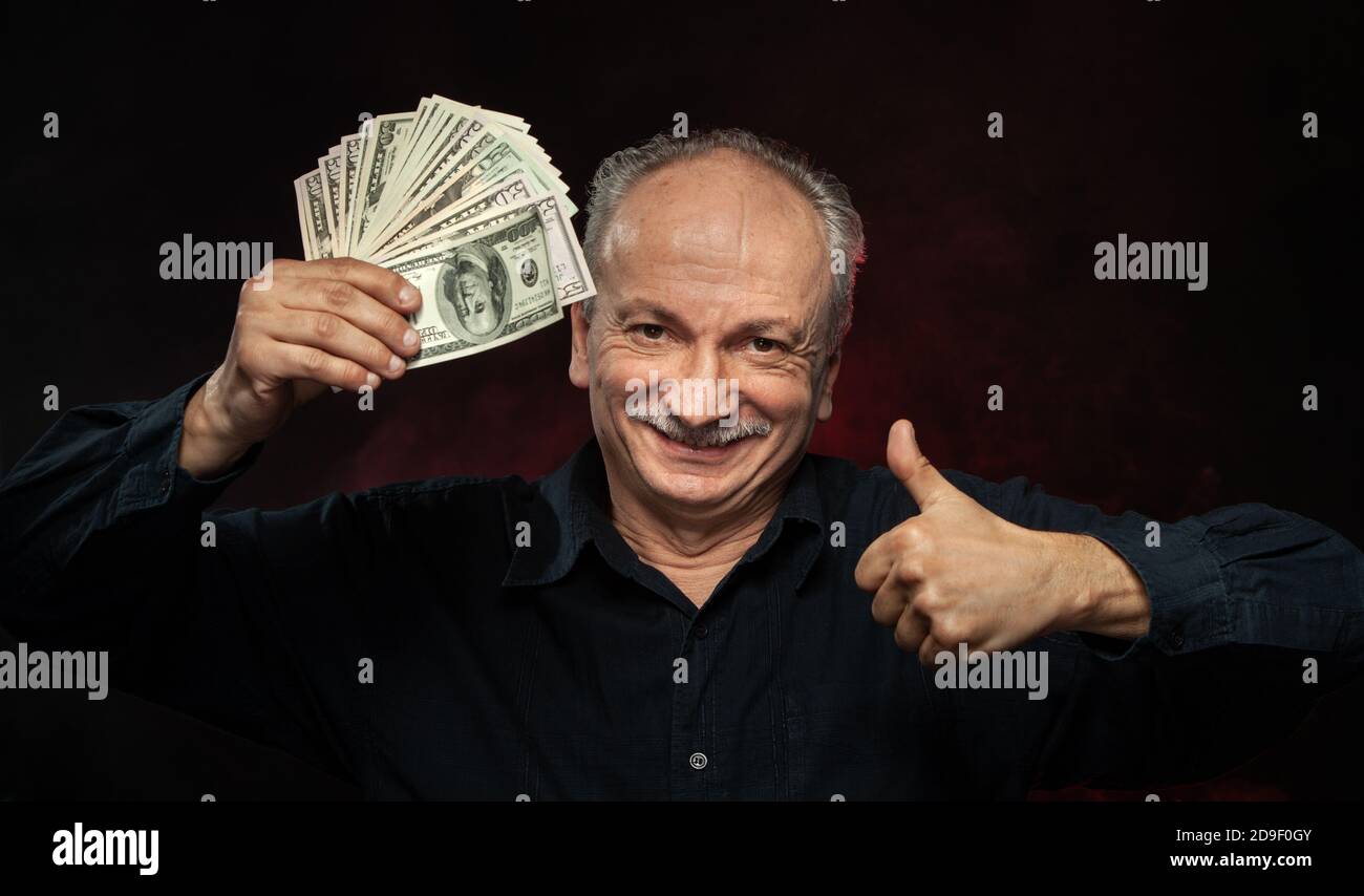 Senior gentleman holding a stack of money. Portrait of an excited old ...