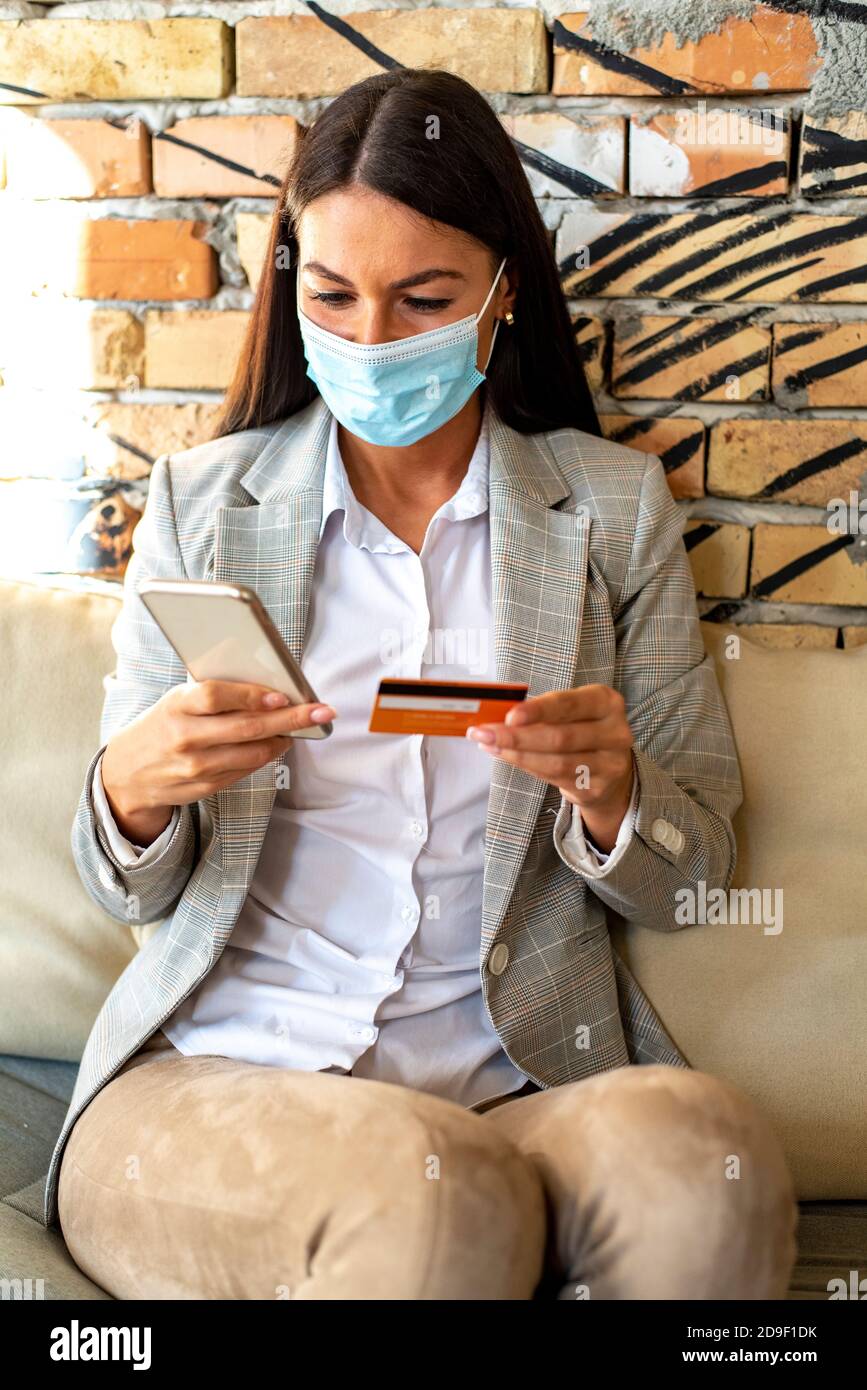 Pretty young woman with protective face mask using mobile phone anc ...