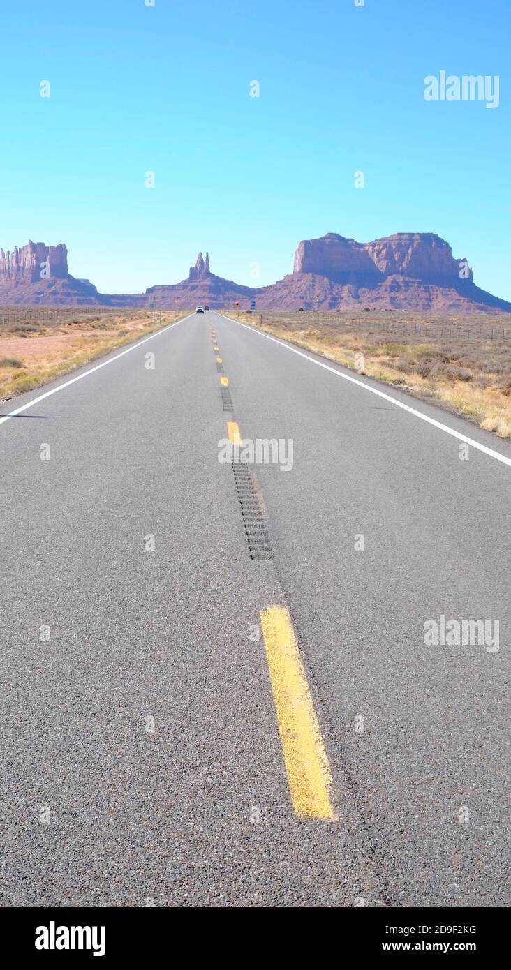 Highway in Southern Utah with broken yellow line and Monument Valley in ...