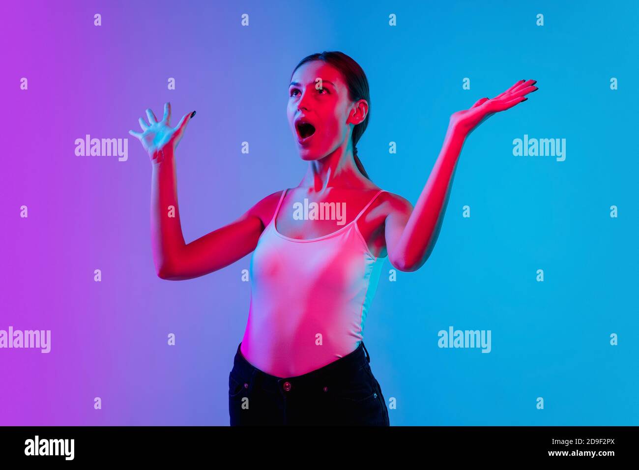 Shocked, astonished. Young caucasian woman's portrait on gradient blue ...
