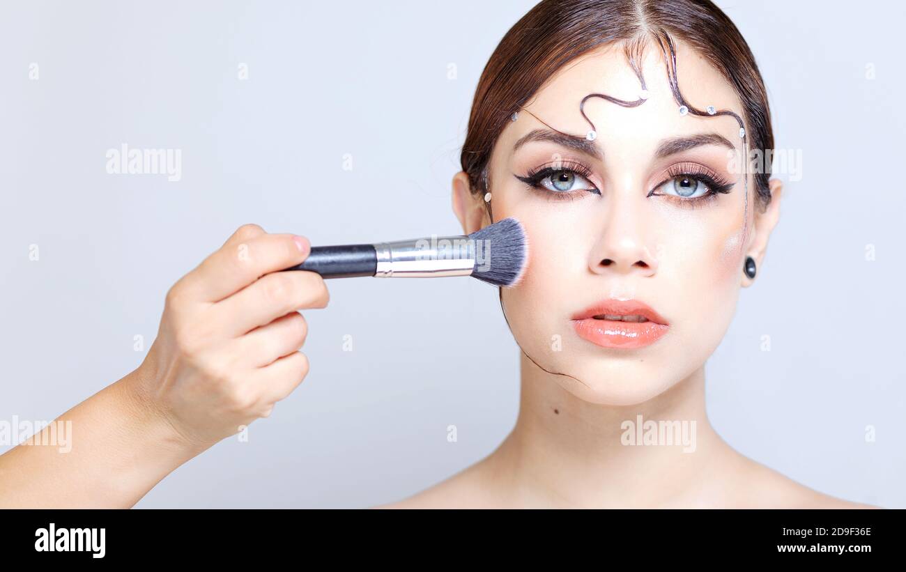 Portrait of a young female getting makeup on her face in a studio Stock ...