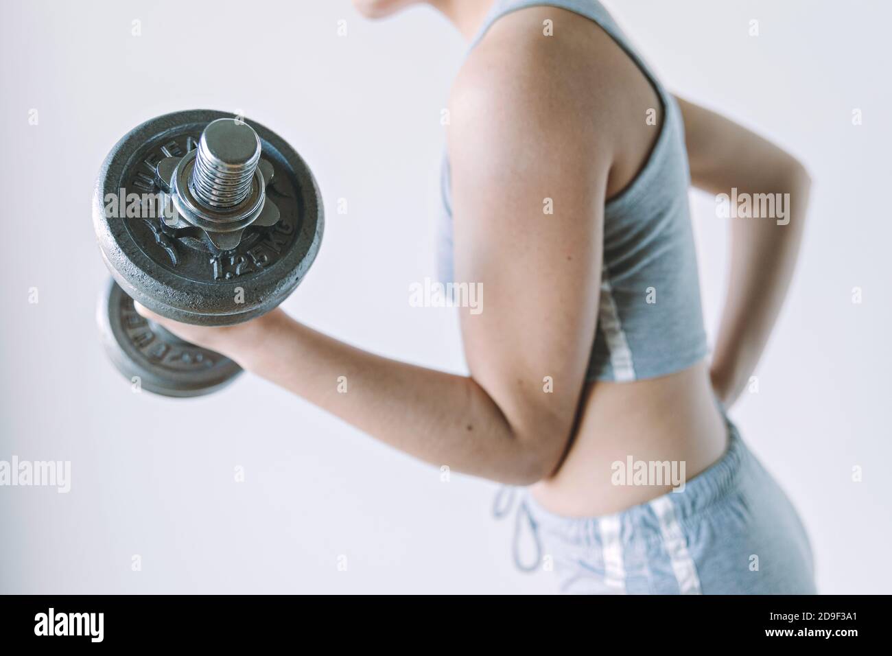 Young attractive lady with a gray workout outfit training with a ...