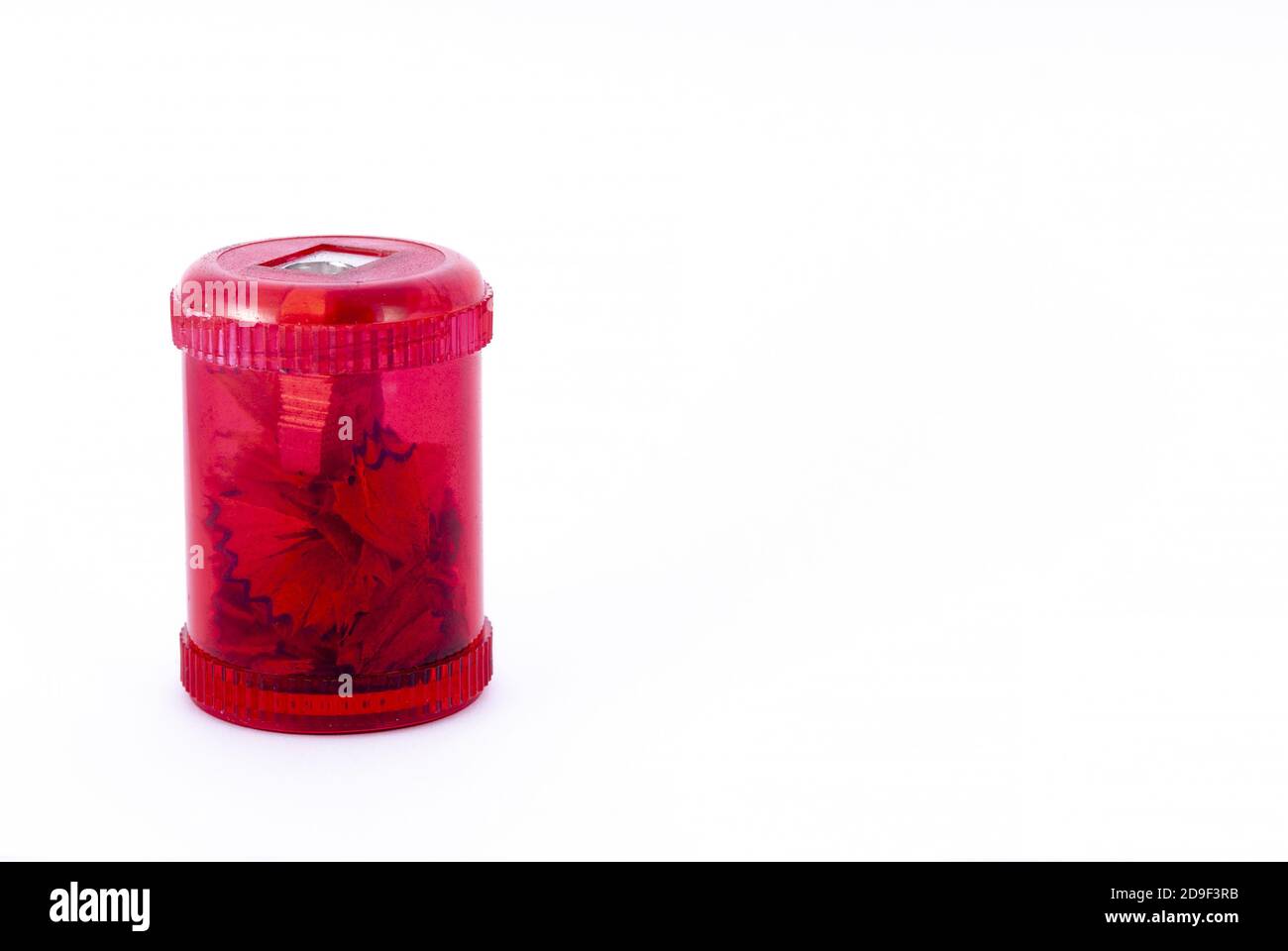 Closeup shot of a red pencil sharpener with shavings isolated on a ...