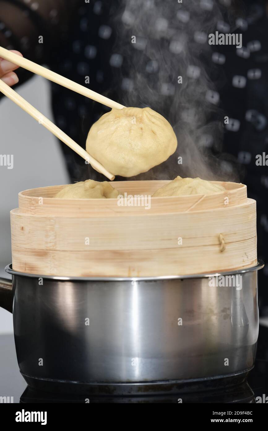 a dumpling being put into a traditional chinese bamboo steamer Stock ...