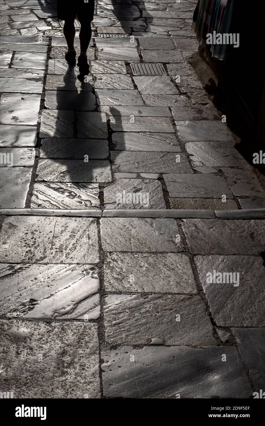 The shadow of a local woman walking along one of the flagstone streets ...