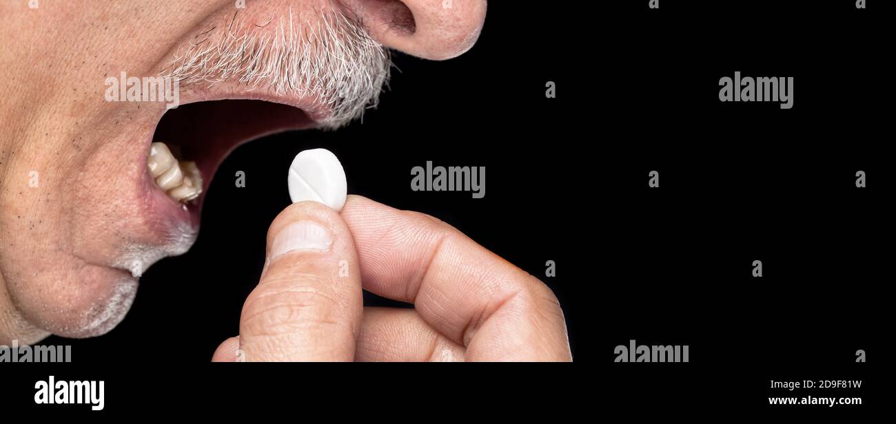 Close-up image of an old man wants to take a pill isolated on black ...