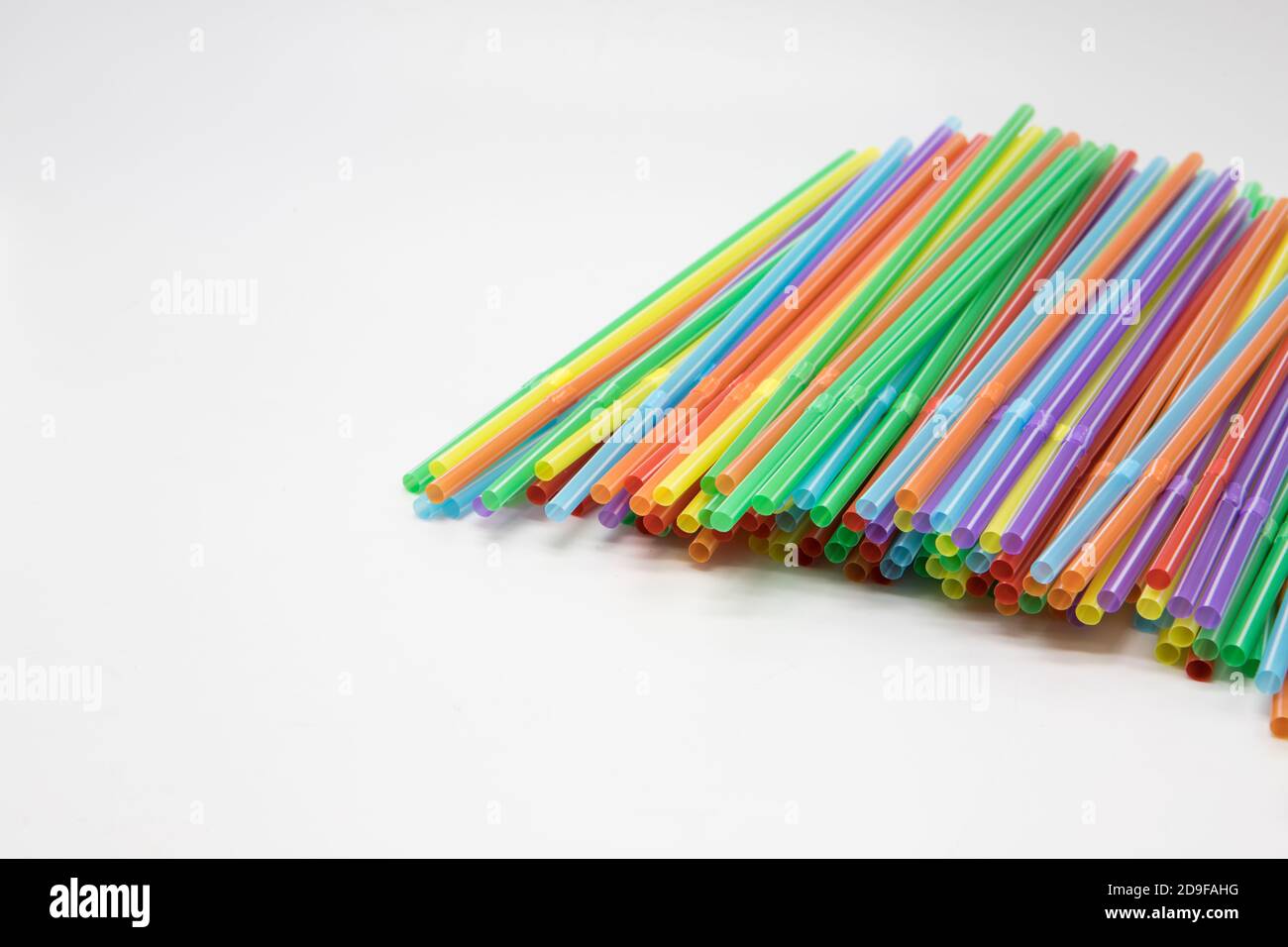 Multicoloured plastic straws on a white background with copy space ...