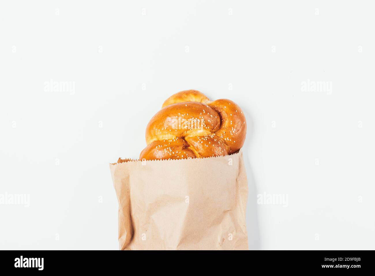 Appetizing fresh bread in brown paper bag on white background, flat lay ...