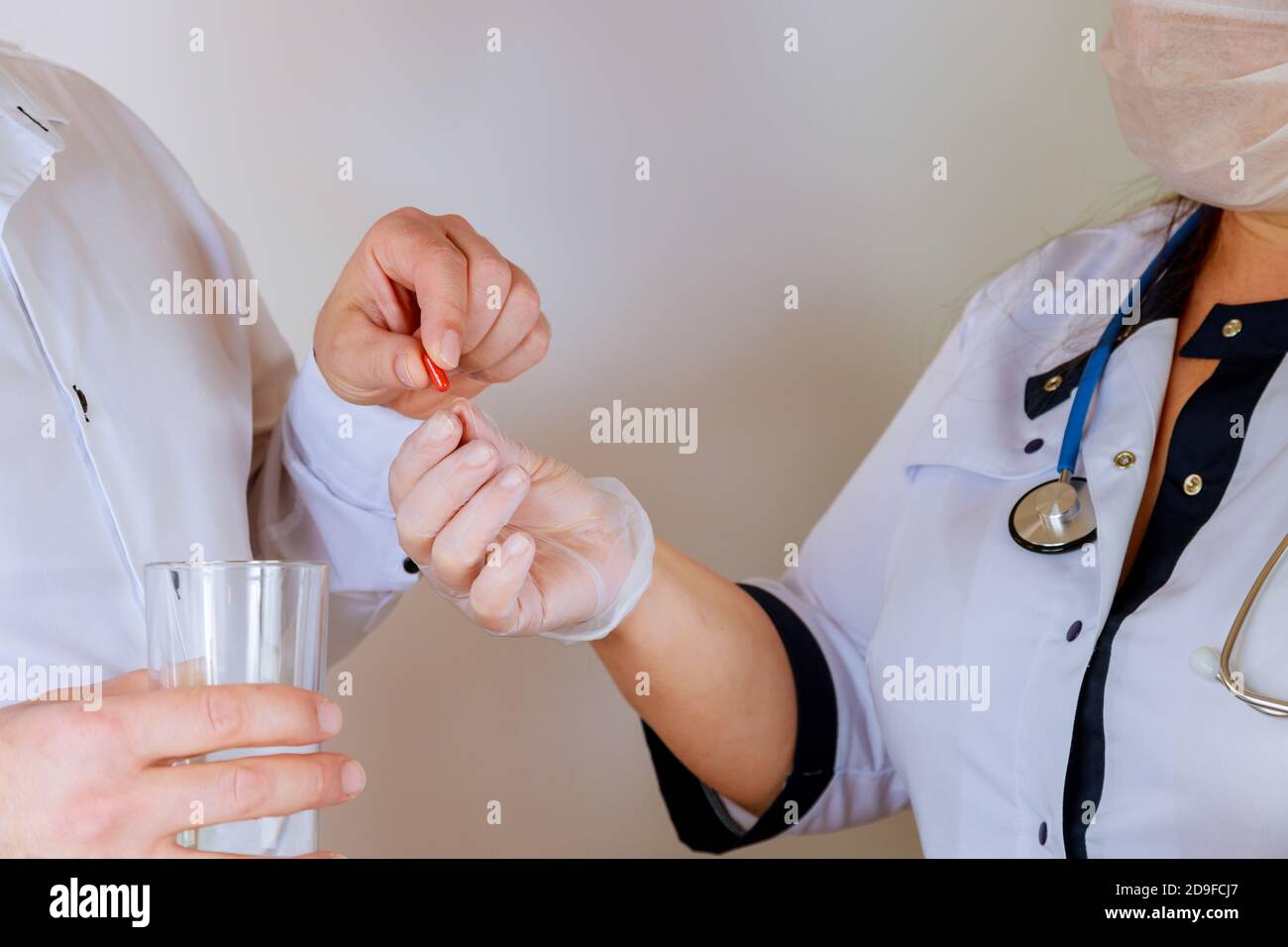 Doctor holding in gives the patient a red pill on white background ...