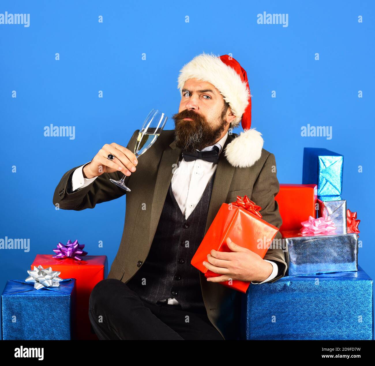 Xmas corporate party concept. Santa in retro suit holds blue and red ...