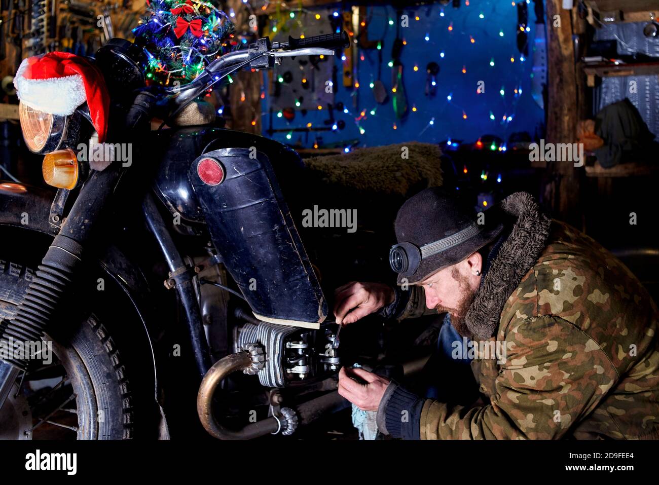 A man repairs an old motorcycle in the garage on New Year's Eve Stock ...