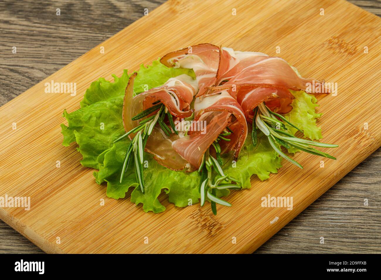 Sliced pork Jamon meat with rosemary Stock Photo - Alamy