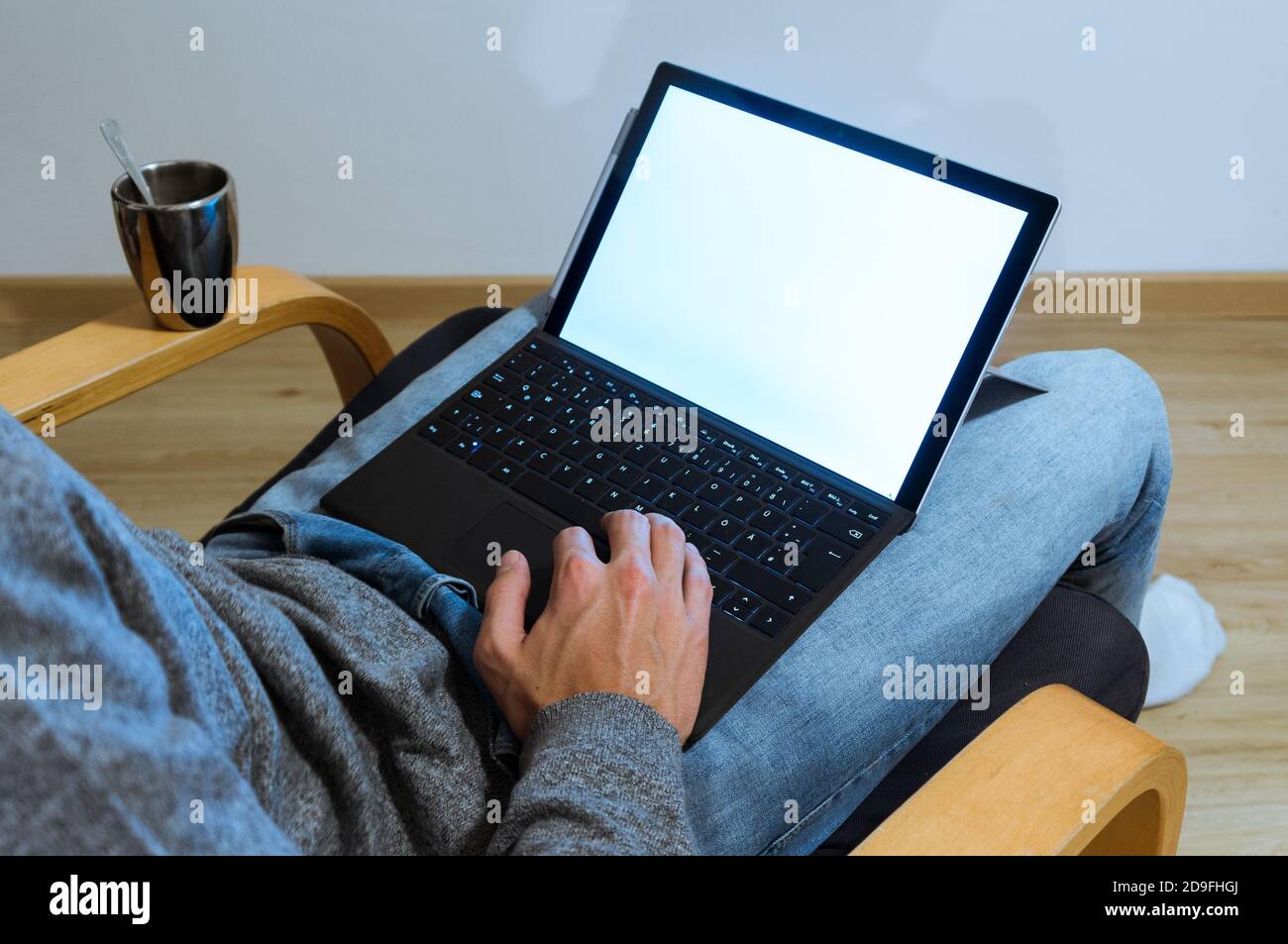 Young man holding laptop in lap, working on it, photographed from ...