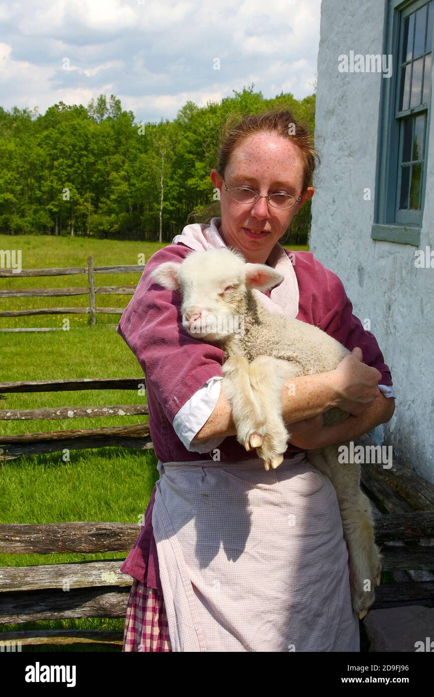 woman holding lamb; period dress; baby farm animal, volunteer ...