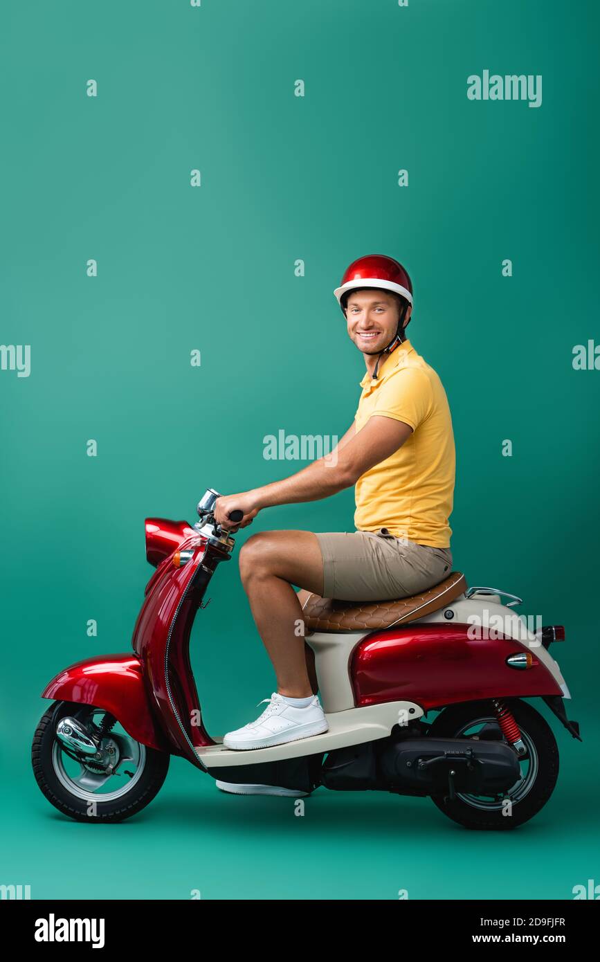 happy delivery man in helmet riding motorbike on blue Stock Photo - Alamy