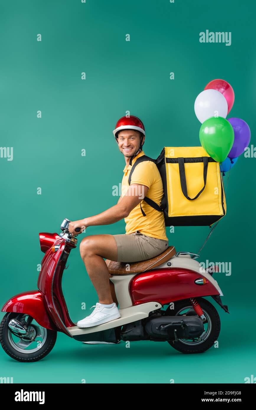 happy delivery man with backpack riding scooter with balloons on blue ...