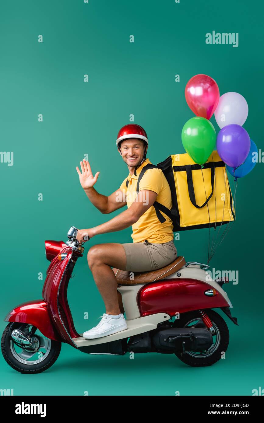 happy delivery man with backpack riding scooter with balloons and ...