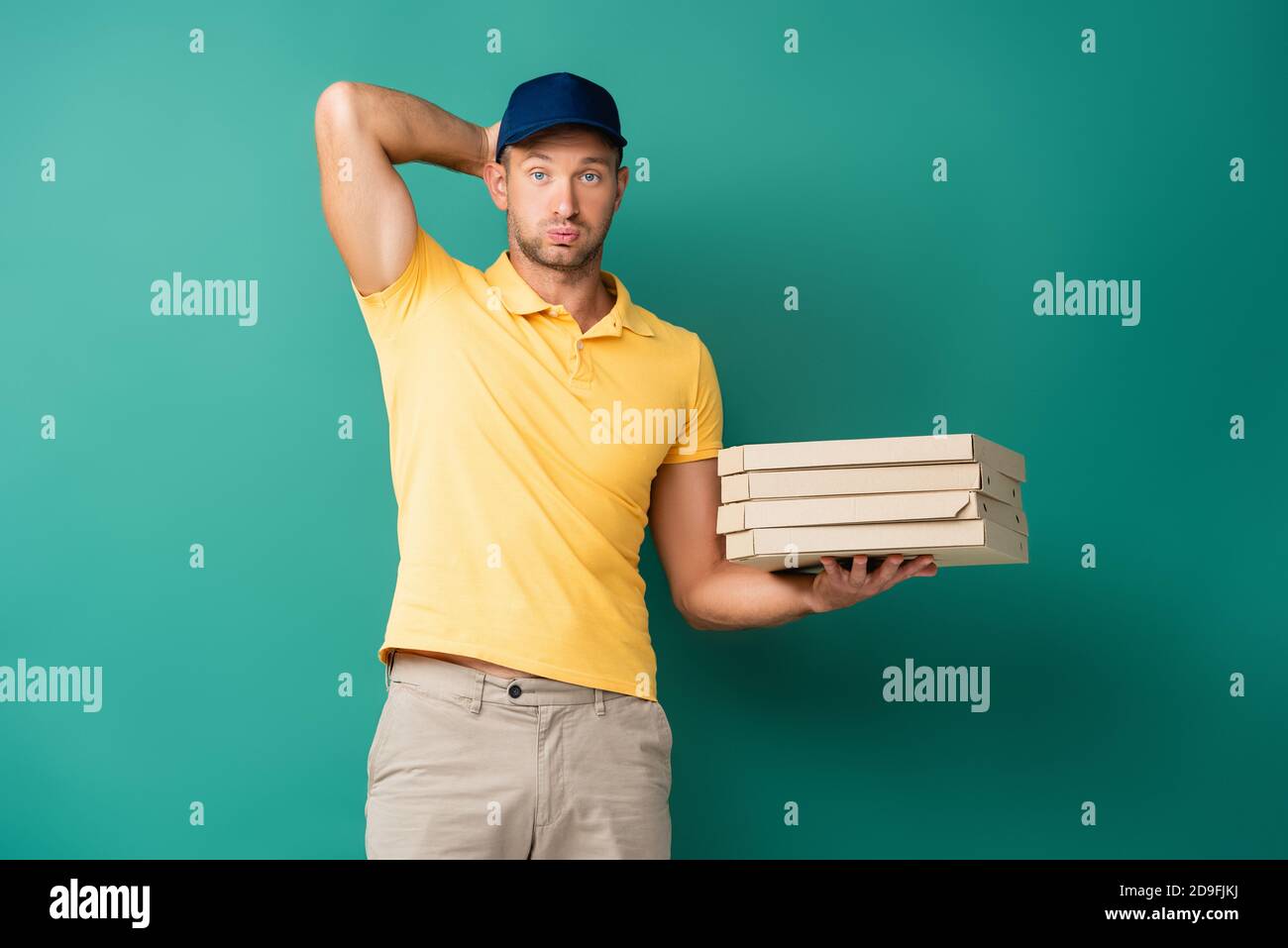 confused delivery man in cap holding pizza boxes on blue Stock Photo ...