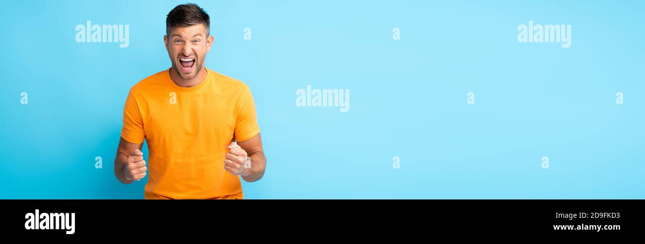 excited man with open mouth and clenched fists on blue, banner Stock ...