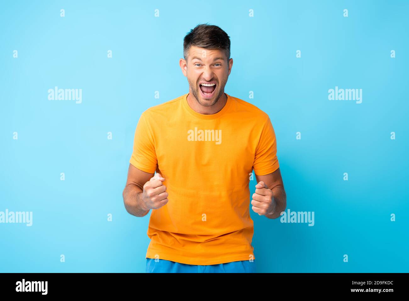 excited man with open mouth and clenched fists on blue Stock Photo - Alamy